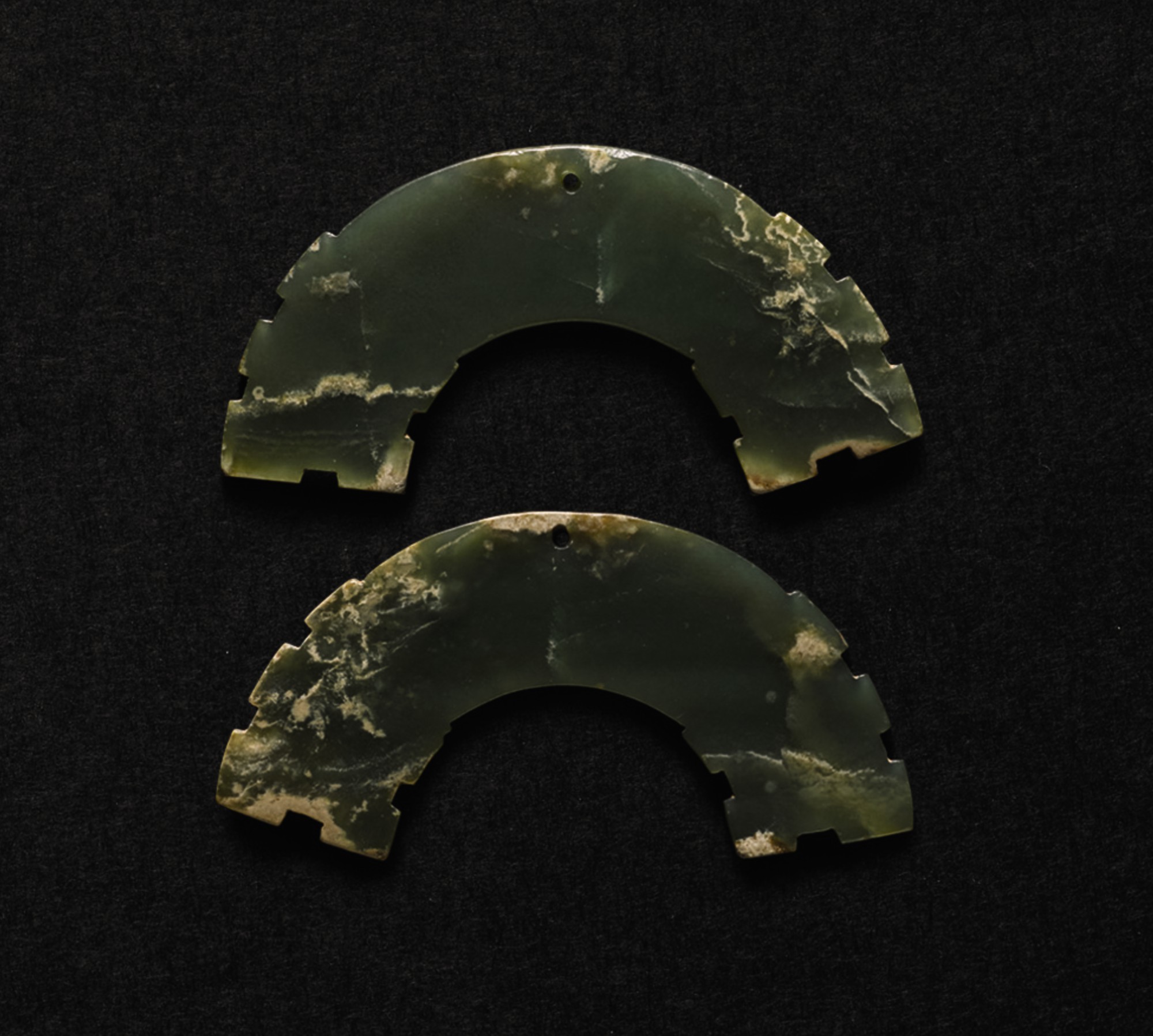 A PAIR OF DARK GREEN JADE ARC-SHAPED PENDANTS, HUANG EASTERN ZHOU ...