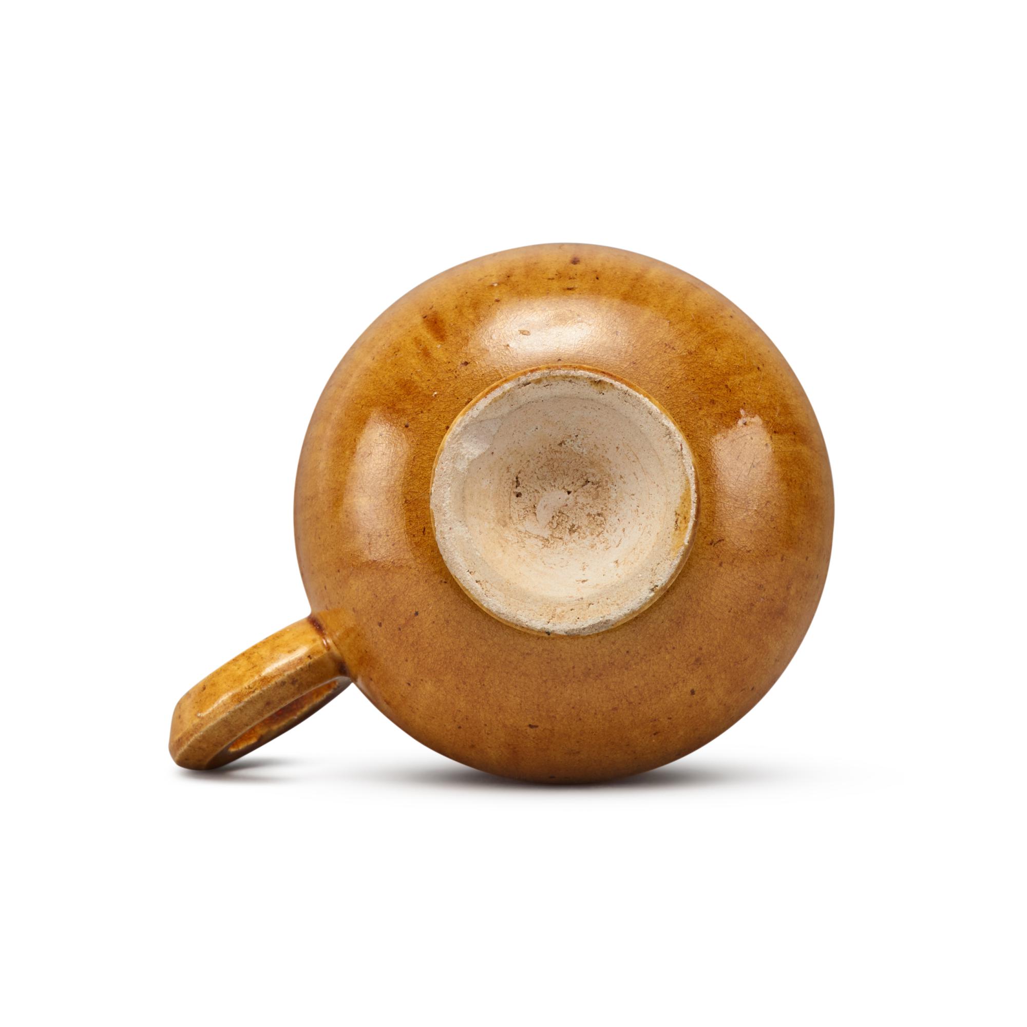 A green- and amber-glazed pottery cup with ring handle, Tang dynasty ...