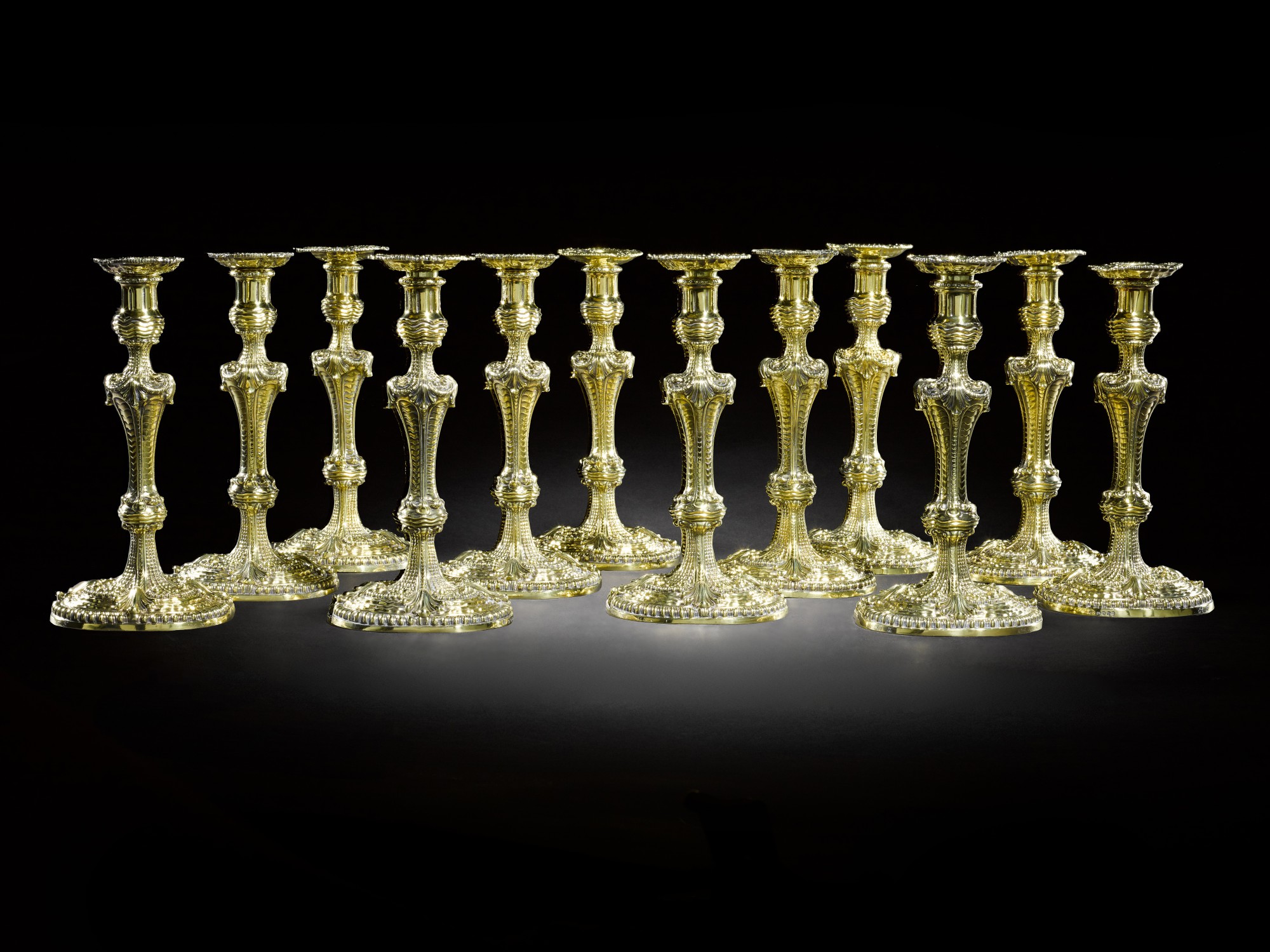 Royal: A set of twelve silver-gilt candlesticks, two William Solomon ...