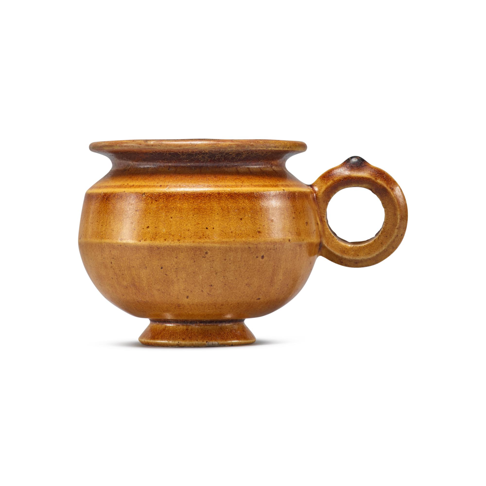 A green- and amber-glazed pottery cup with ring handle, Tang dynasty ...