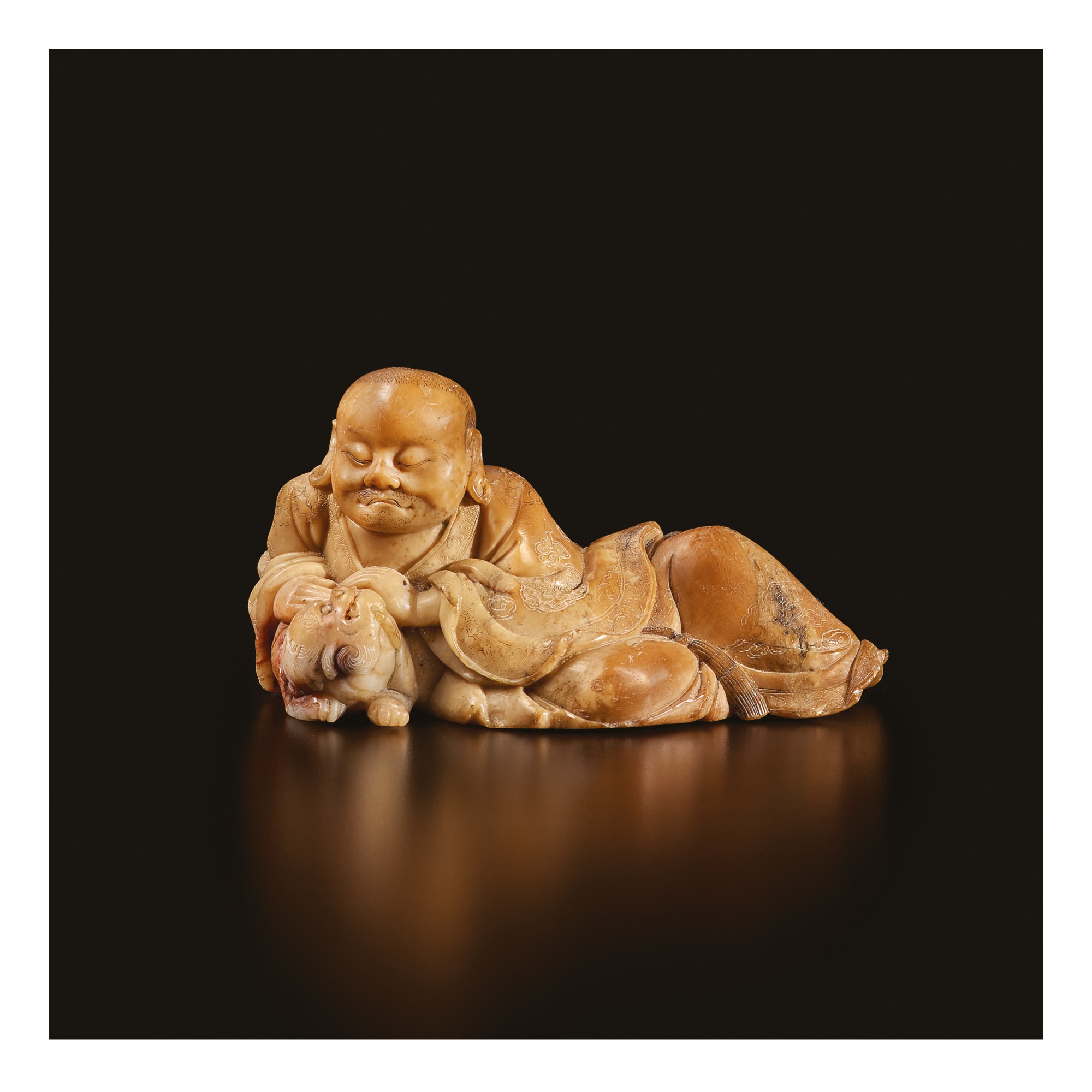 A BEIGE SOAPSTONE FIGURE OF A RECLINING LUOHAN, 17TH / 18TH CENTURY ...