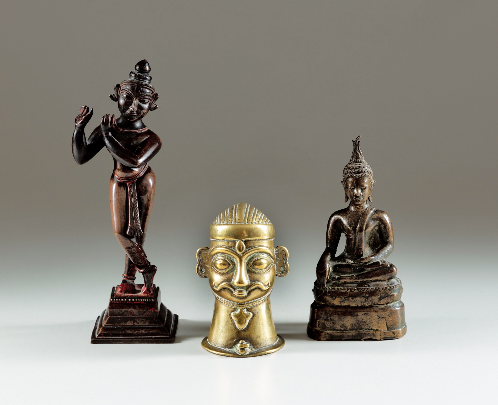 A standing bronze Krishna, a brass Shiva Linga and a bronze seated ...