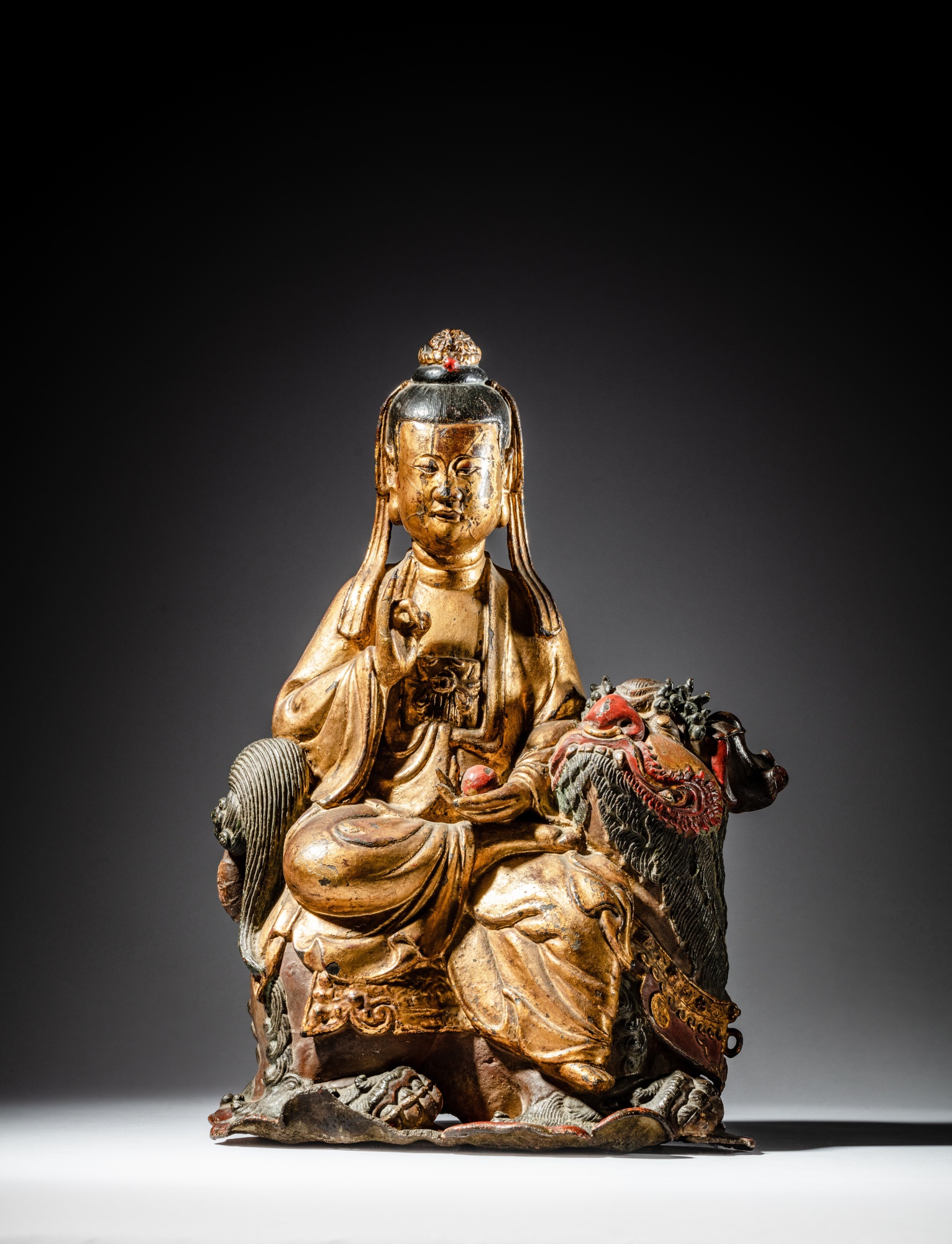 A gilt and polychrome lacquer bronze figure of a bodhisattva on a lion ...