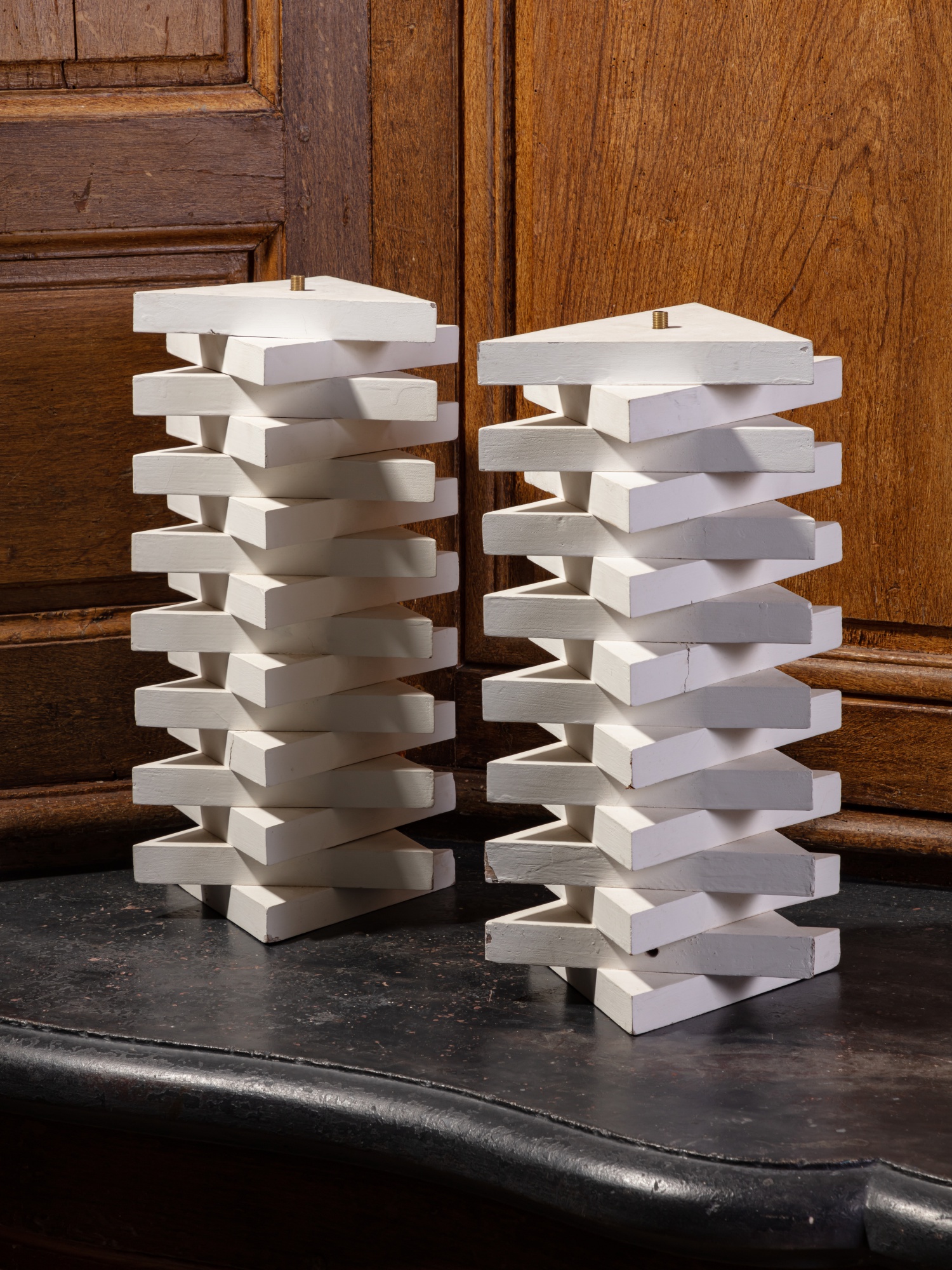 A pair of white painted wood triangular lamp bases, designed by Andrew ...